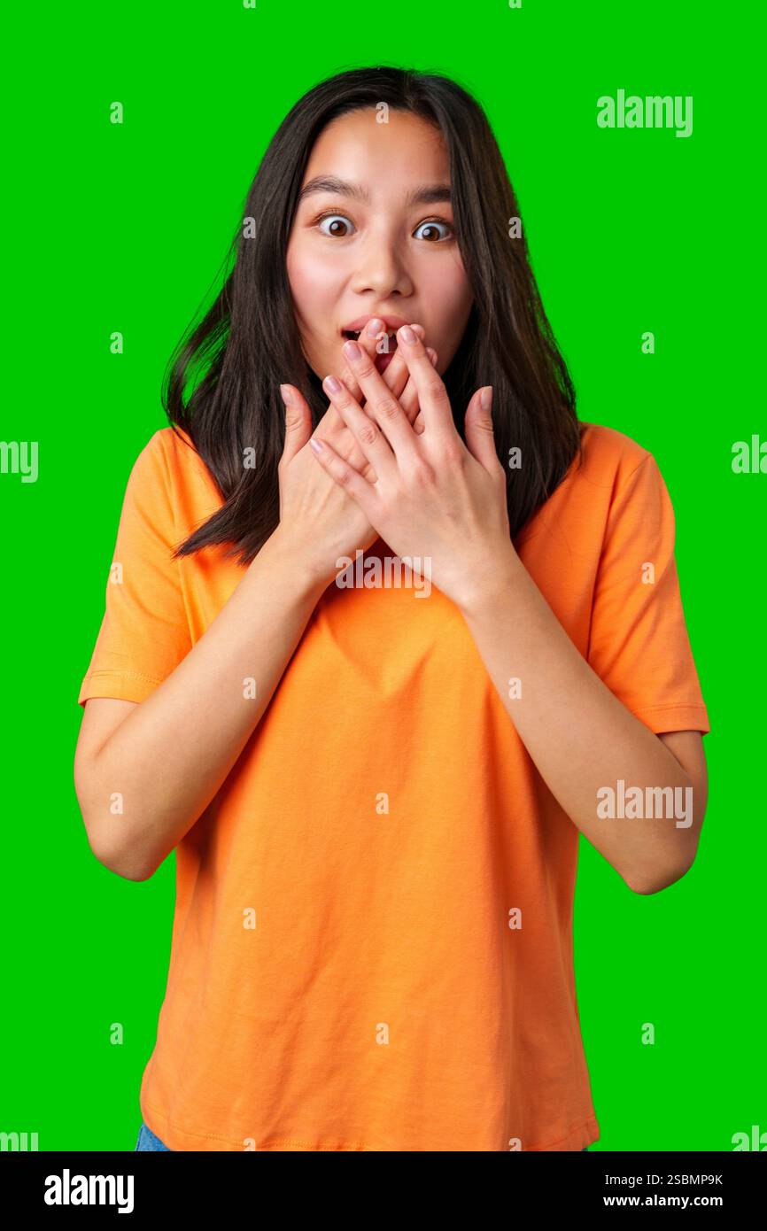 Surprised young woman expressing shock with hands over mouth against ...