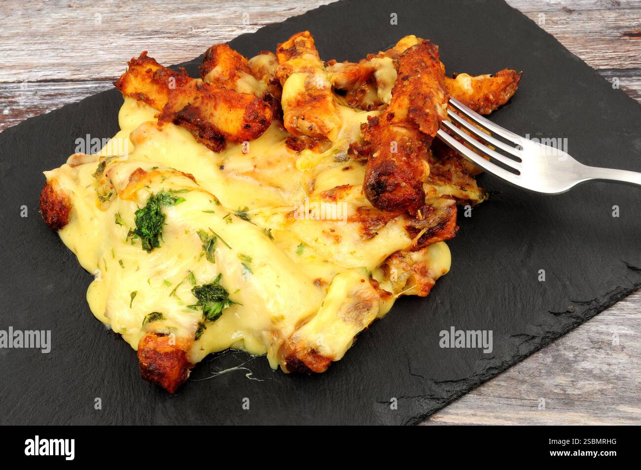 Portion of dirty cheesy fries on a slate serving board, fried battered ...