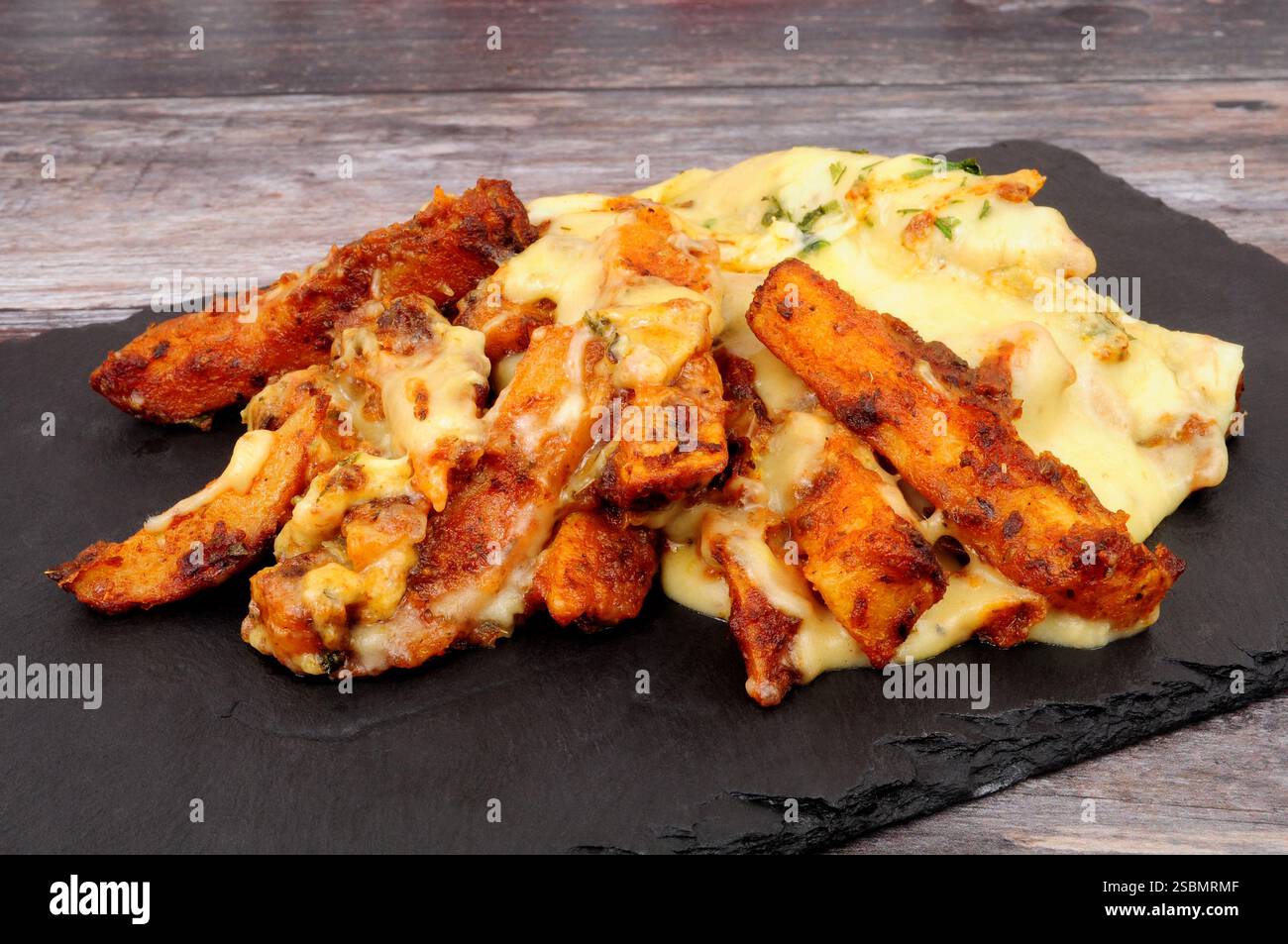 Portion of dirty cheesy fries on a slate serving board, fried battered ...