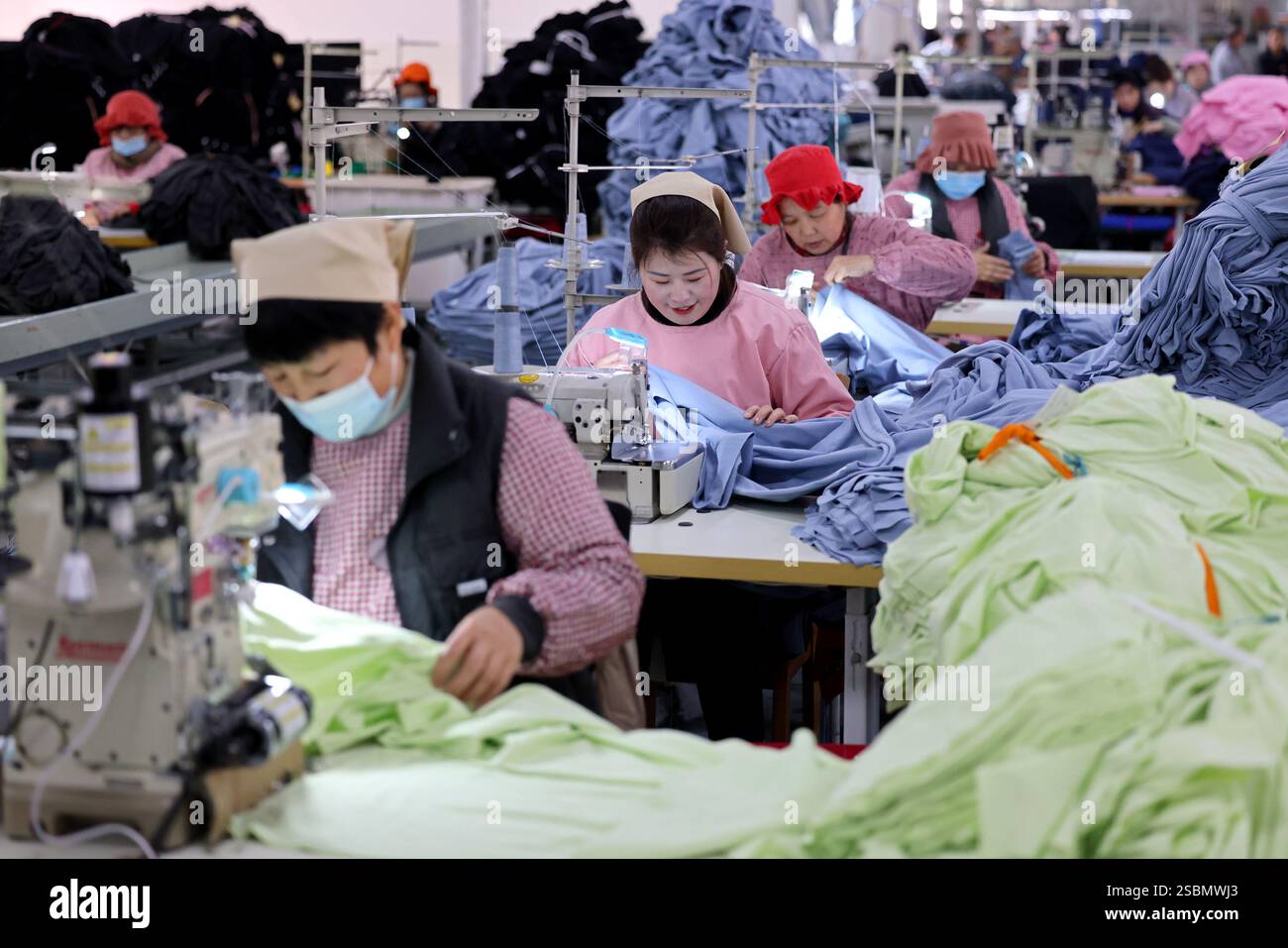 Workers of a textile company produce garments for export at a workshop in Zaozhuang, East China ...