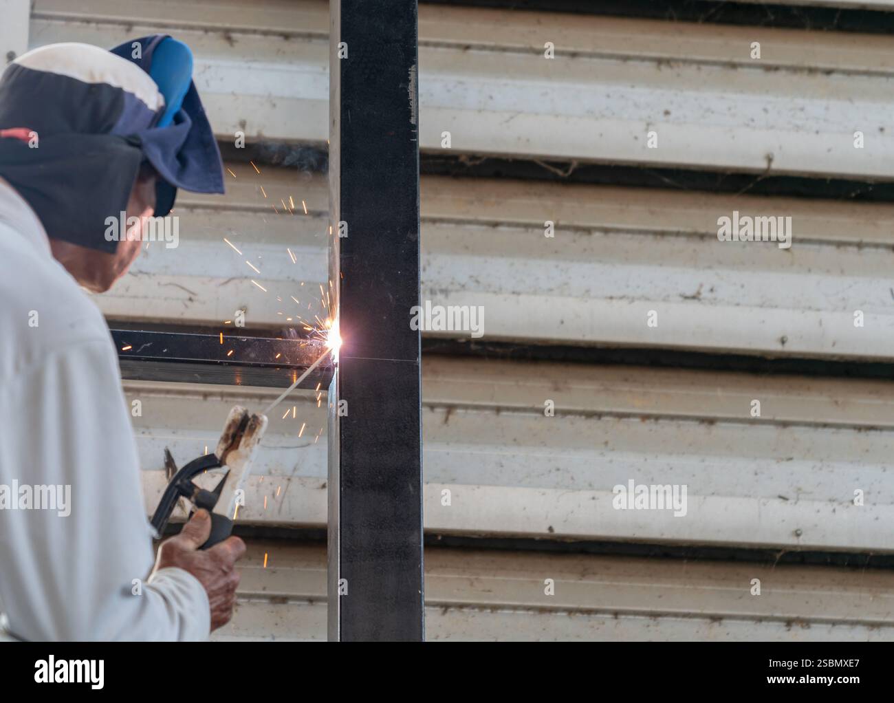 Worker welding black pole without personal protective equipment in ...