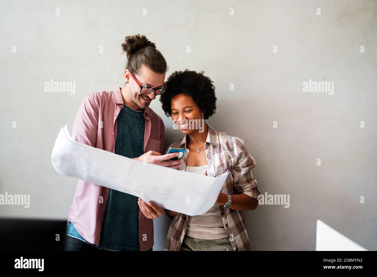 Engineers helping design work on blueprints, collaborate on structural ...