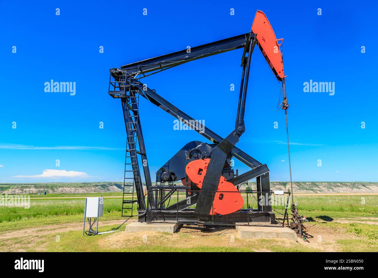 Black and red oil rig with a ladder on the side. The rig is in a field ...