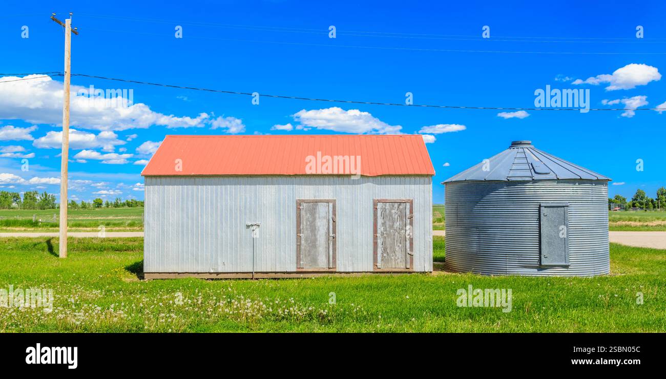Red barn with a metal roof sits in a field. A large metal tank is next ...