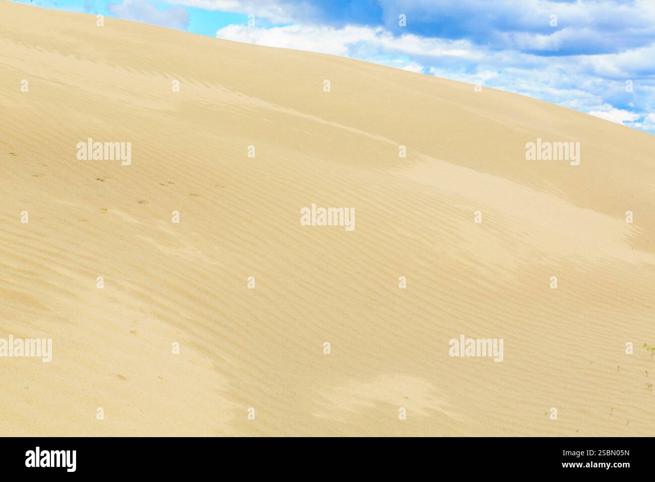 Sandy hill with a few clouds in the sky. The clouds are scattered and ...