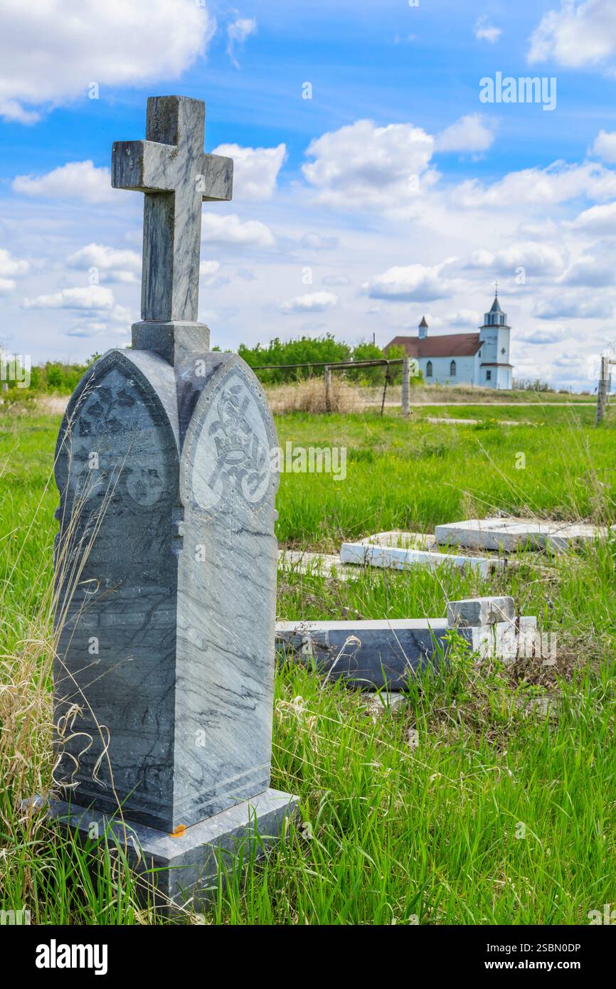 Gray headstone with a cross on top of it. The headstone is in a field ...
