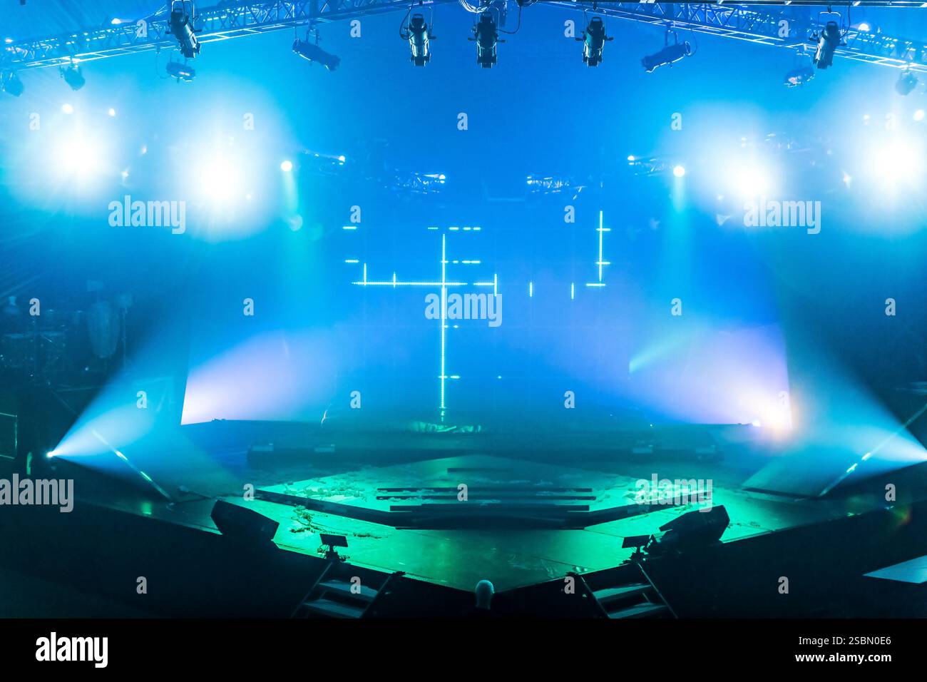 Stage with a large cross on the screen. The stage is lit up with blue ...