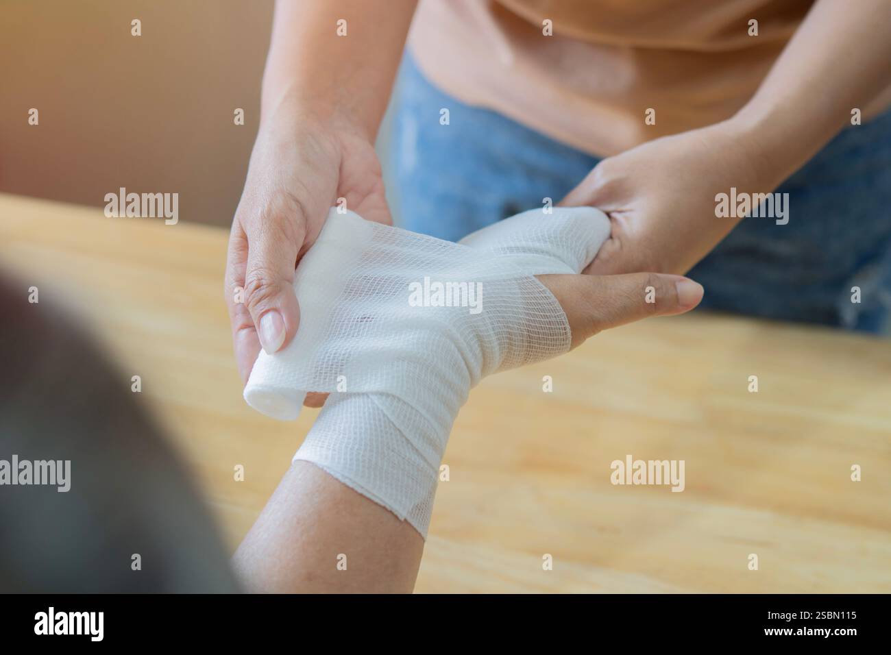 Daughter wrapping her mom wrist and arm with bandage around injured ...