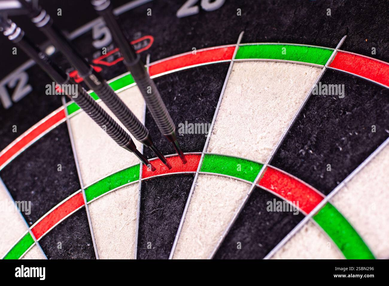 Official dartboard with closeup view of three darts sticking in the triple twenty field (180 ...
