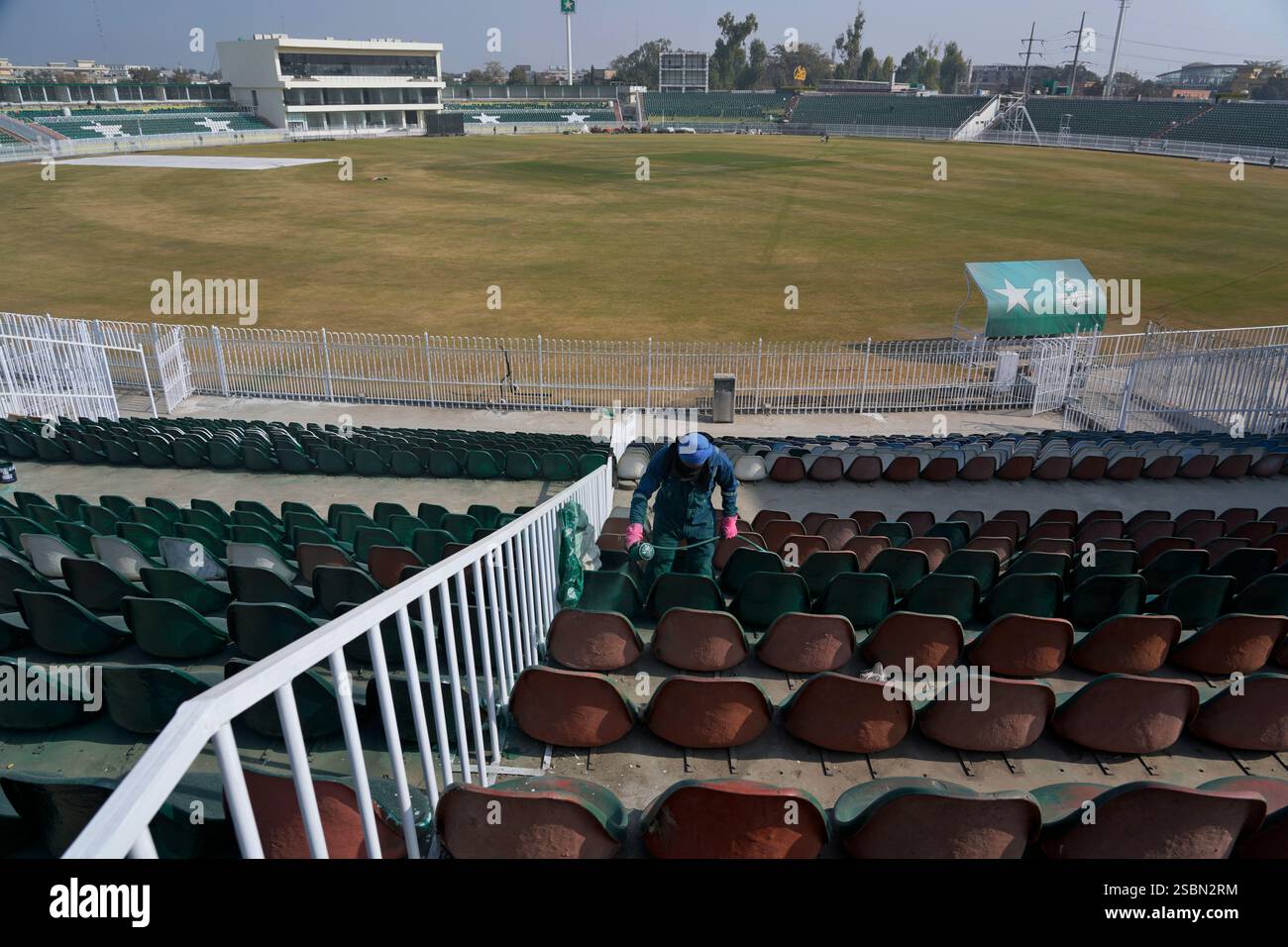 A laborer paints chairs in an enclosure of the Pindi Cricket Stadium ...