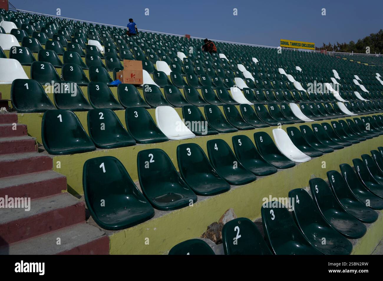 A laborer paints numbers on newly installed chairs in an enclosure of ...