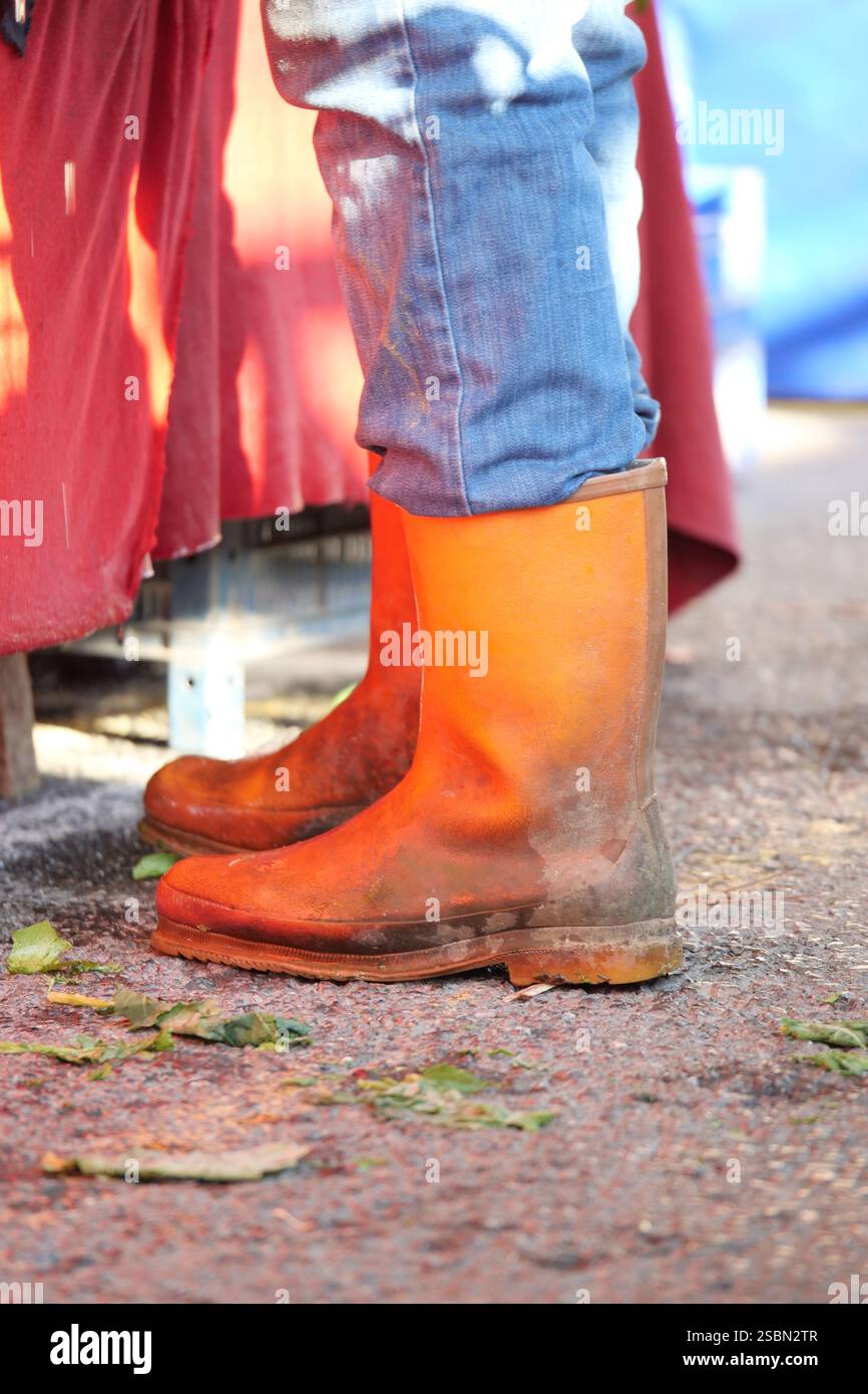 Bright orange boots on muddy ground at an outdoor market Stock Photo ...