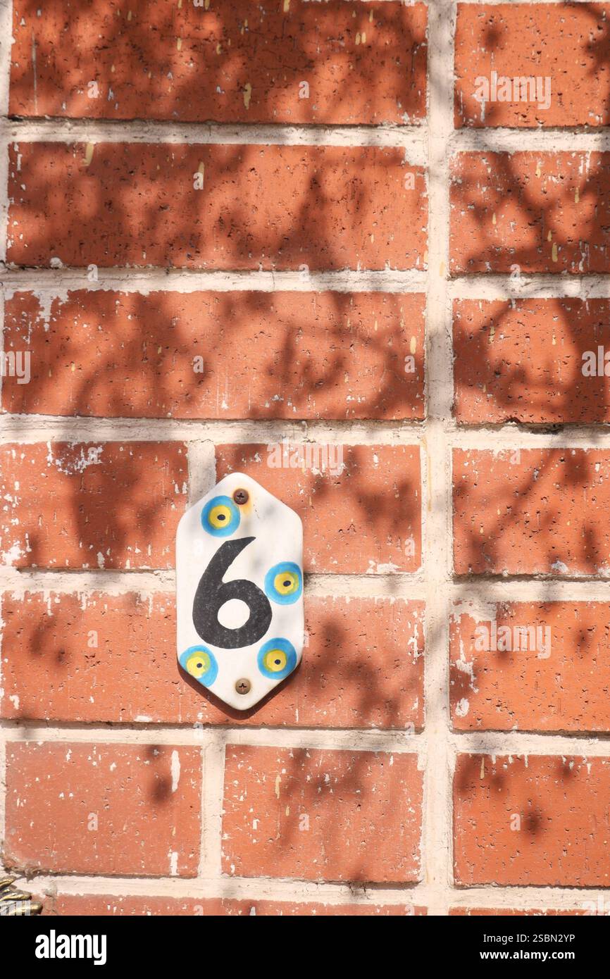 House number six displayed on a brick wall with shadows Stock Photo - Alamy