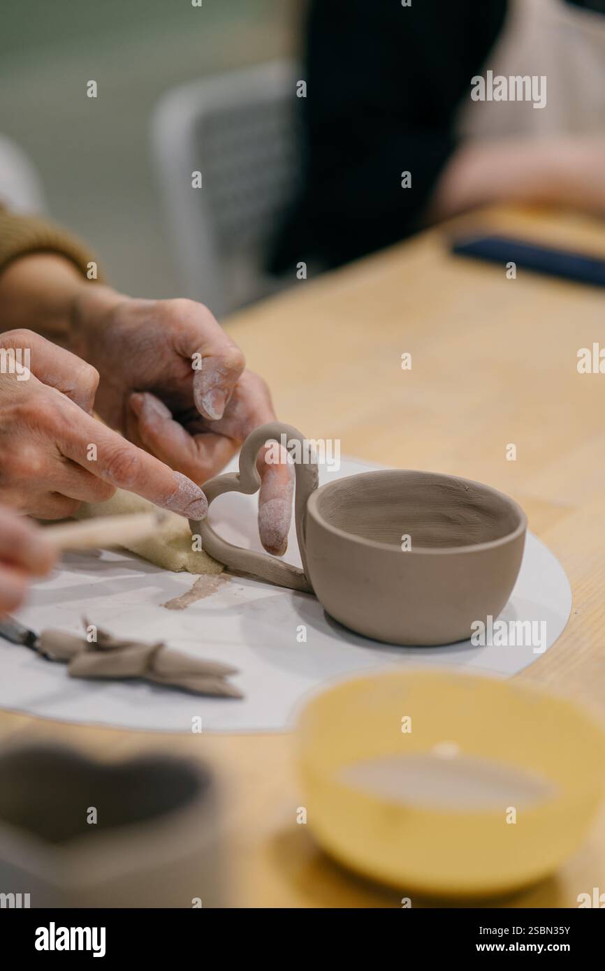 Pottery student modeling clay mug, learning traditional sculpting ...