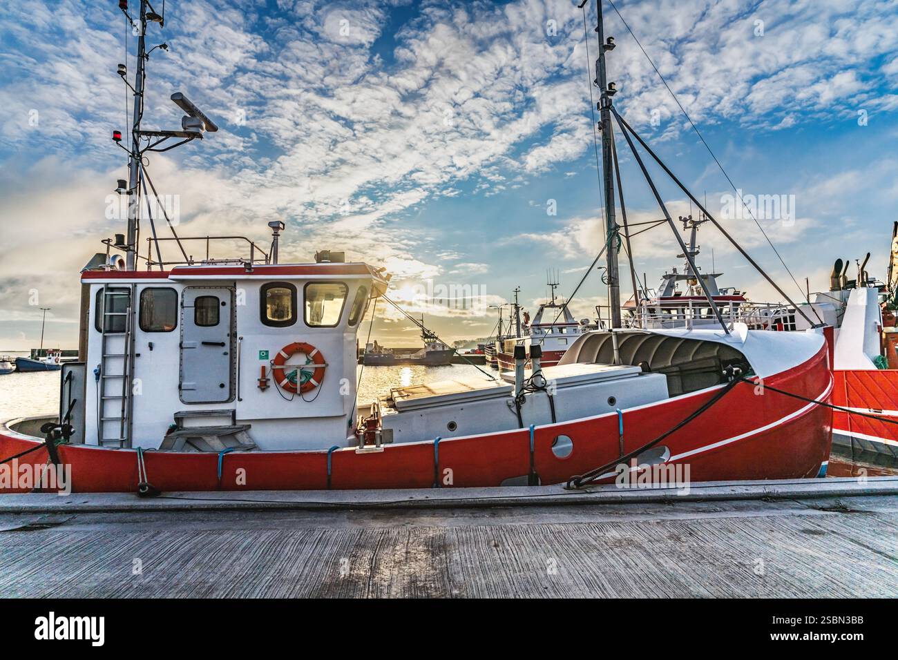 A vivid red fishing boat docked at a harbor, illuminated by soft ...
