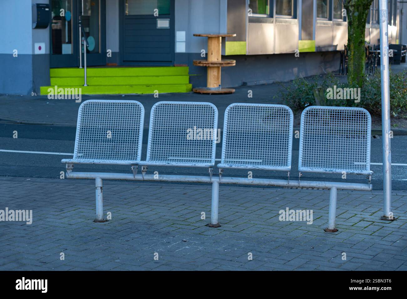 A contemporary metal bench sits along a pavement, enhancing the ...
