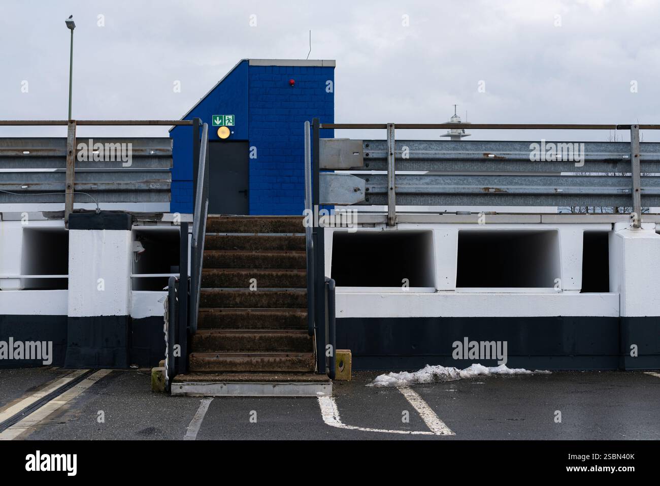 A set of concrete steps leads up to a blue building at a parking structure. The scene is set ...