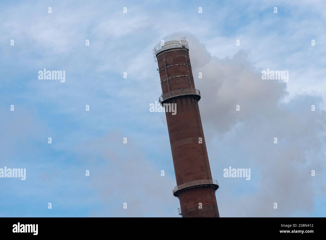 A tall industrial chimney is visible against a clear blue sky, with ...