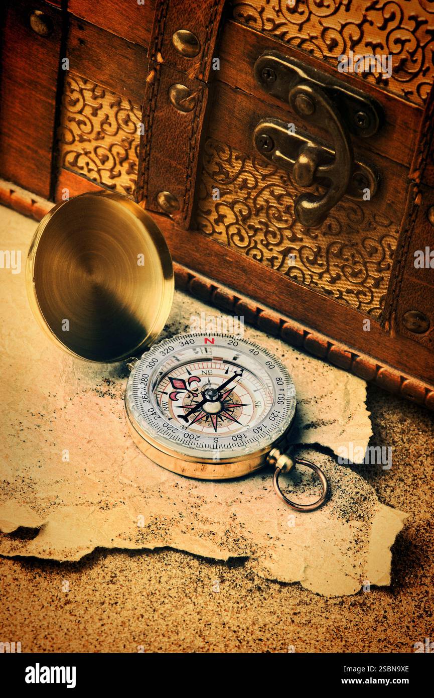 Compass on old sheet crumpled paper against the background of sand ...
