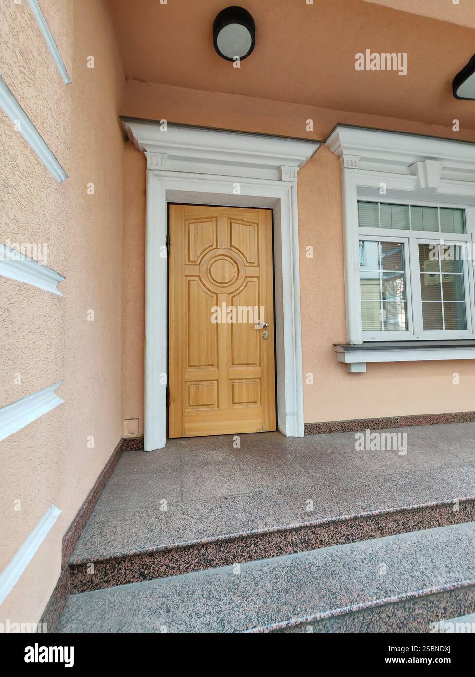 An ornate wooden door in a textured peach building featuring decorative ...
