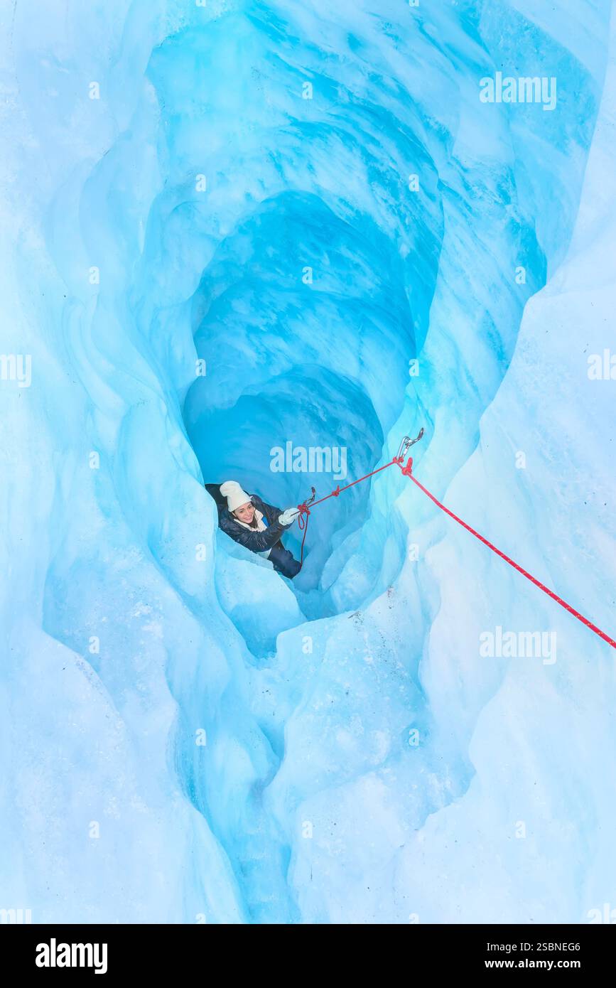 New Zealand, South Island, Climber ascending an ice cave, Fox Glacier ...