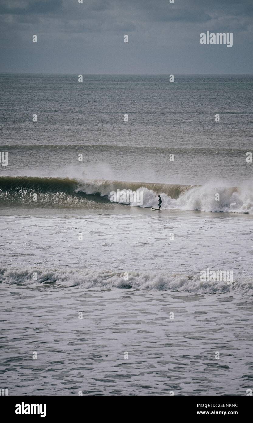 A surfer is riding a wave in the ocean. The water is choppy and the sky ...