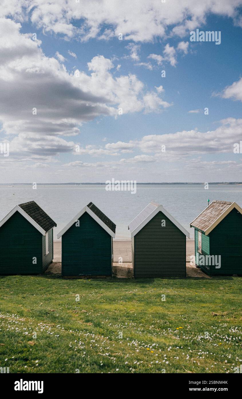 A row of small beach houses are lined up on a grassy hill overlooking ...