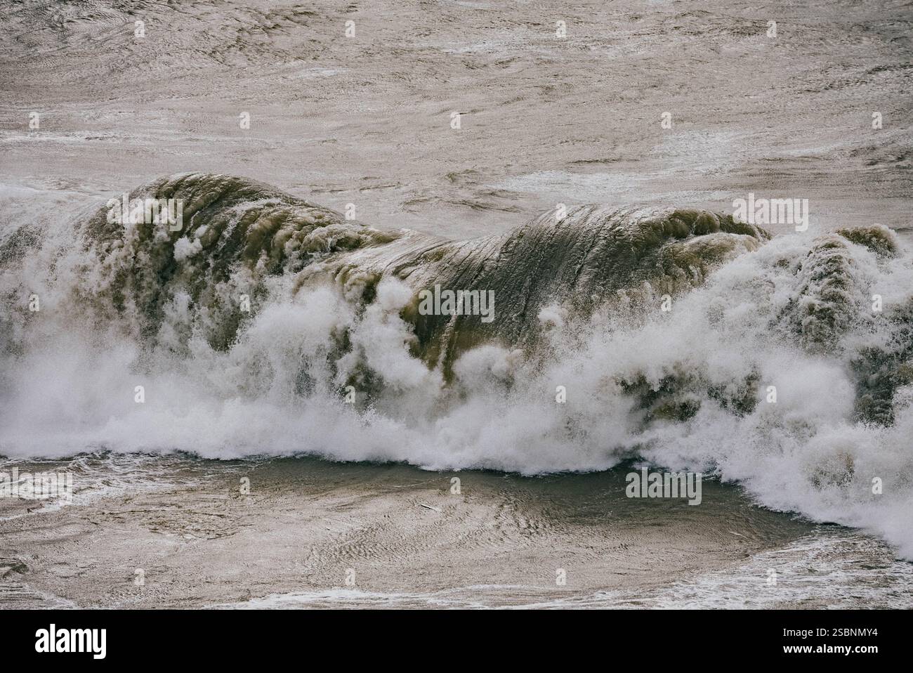 A large wave crashing onto the shore, with the water reaching up to the ...