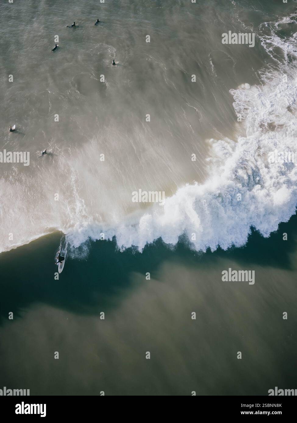 A surfer is riding a wave in the ocean. The water is choppy and the sky ...