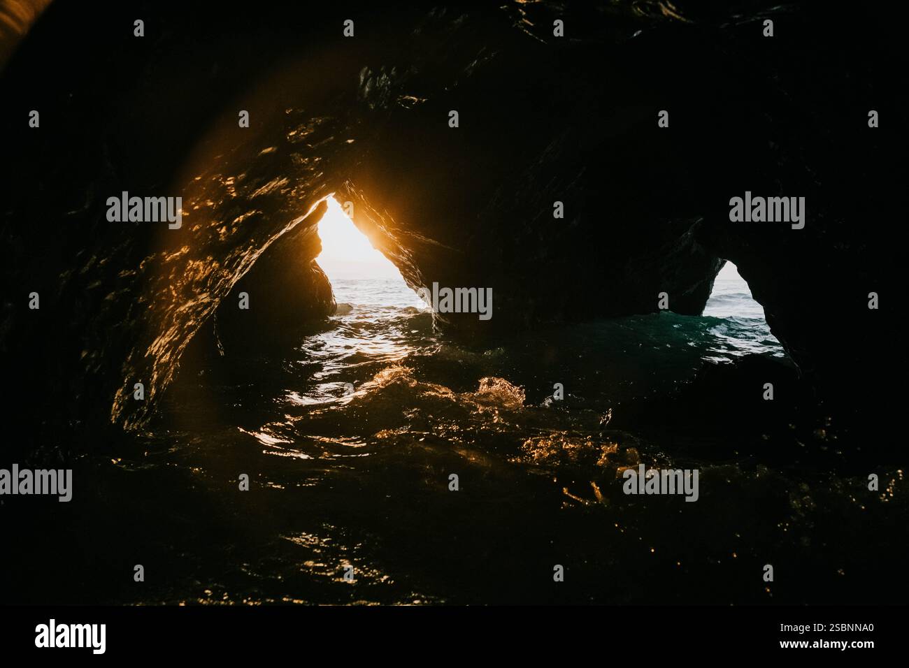 A cave with a small opening in it and the sun shining through it. The ...