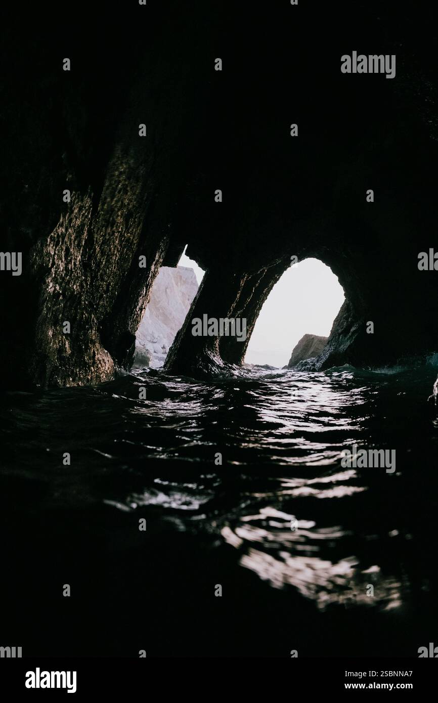 A dark cave with water flowing through it. The water is murky and the ...