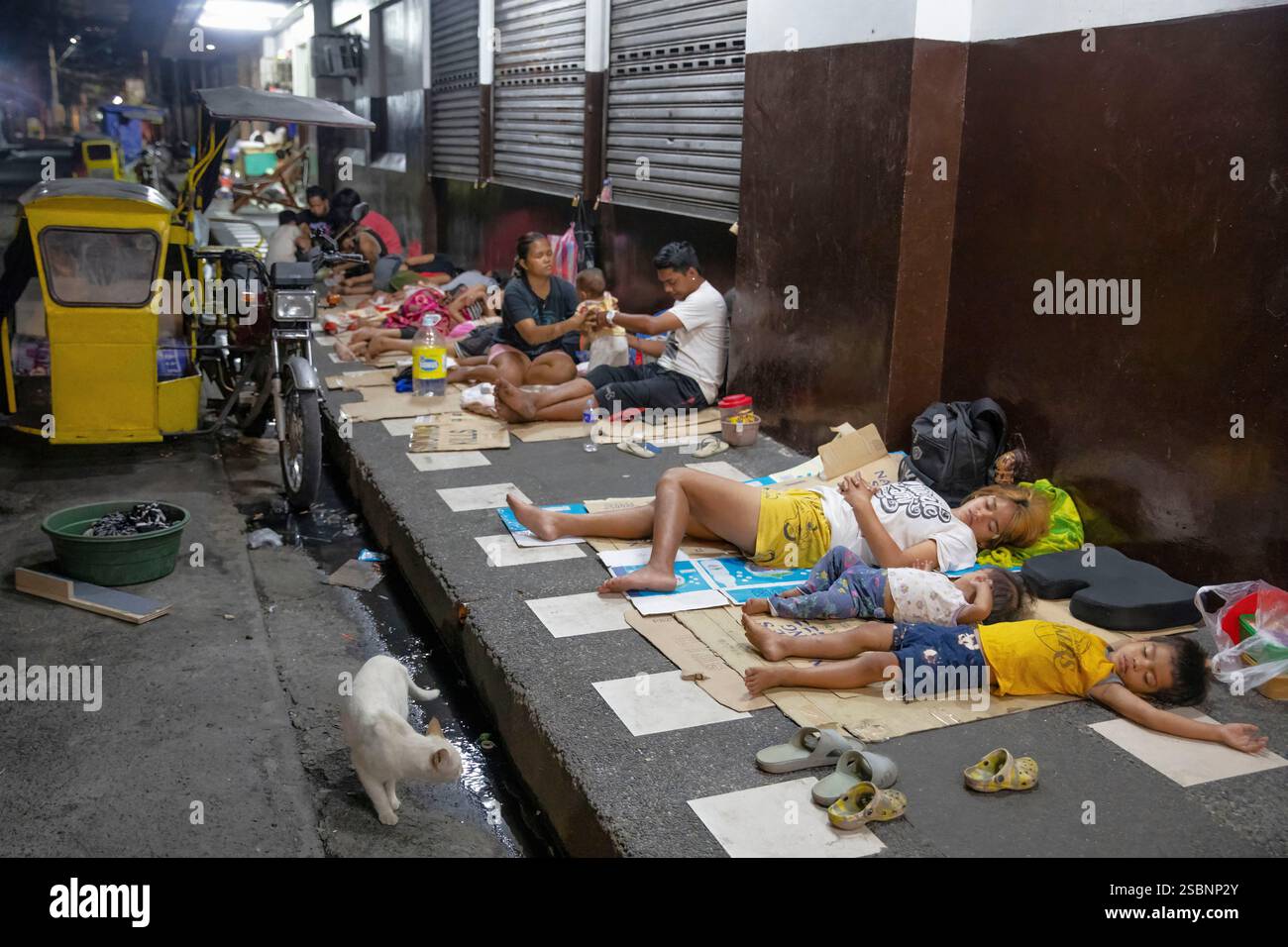 Philippines, Manila, familys lying on a cardboard on a pavement, met ...