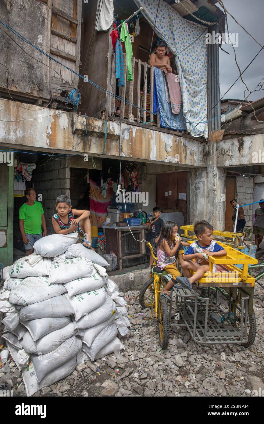 Philippines, Manila, Jundo, children perched on sandbags and a cart in the middle of a slum ...