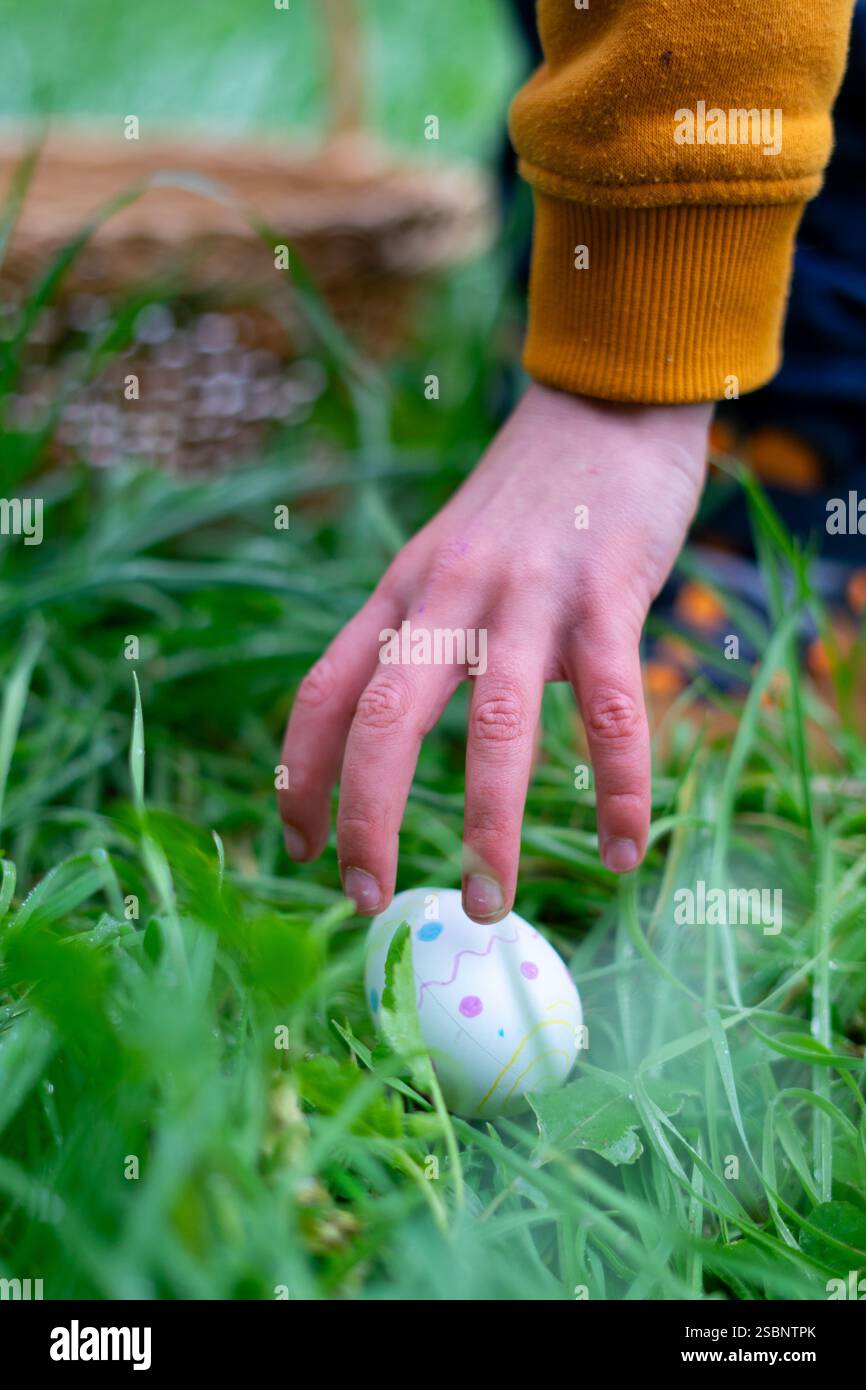 Kid finding colorful easter egg hidden in grass during easter egg hunt ...