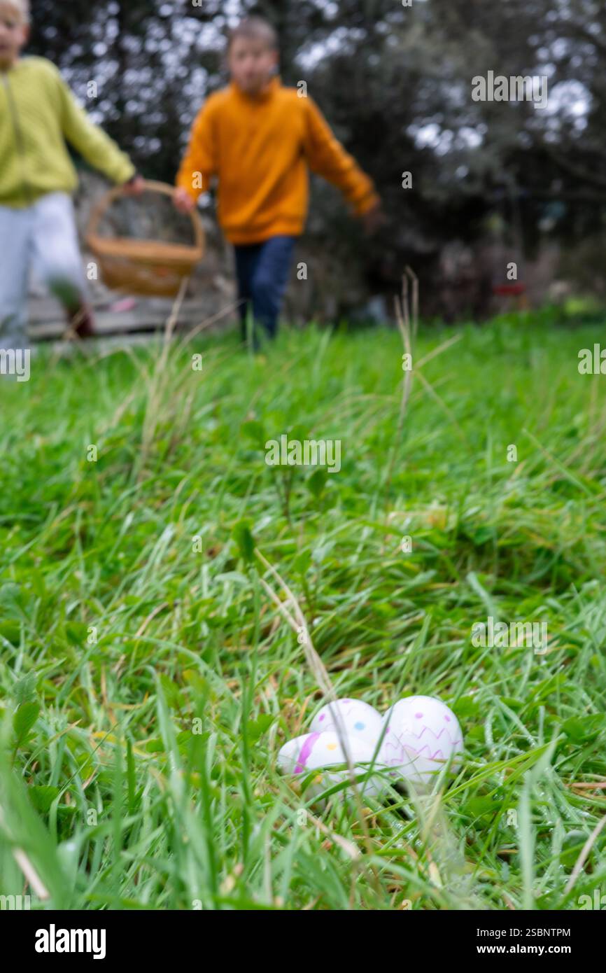Kids running with basket to collect easter eggs hidden in the grass ...