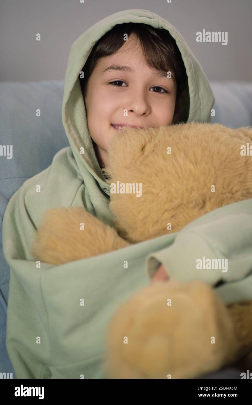 The boy embraces a soft teddy bear, evoking themes of childhood ...