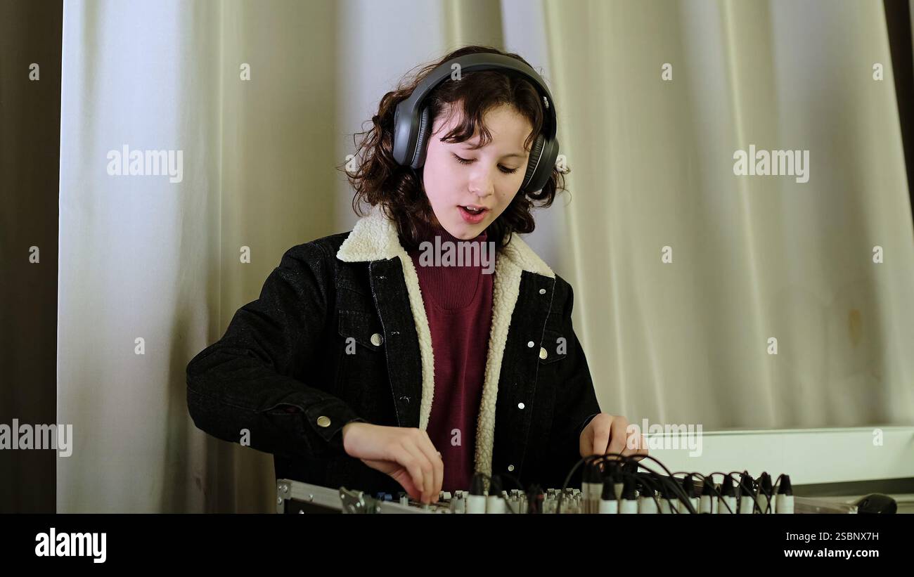A young girl smiles as she adjusts the controls of a soundboard ...