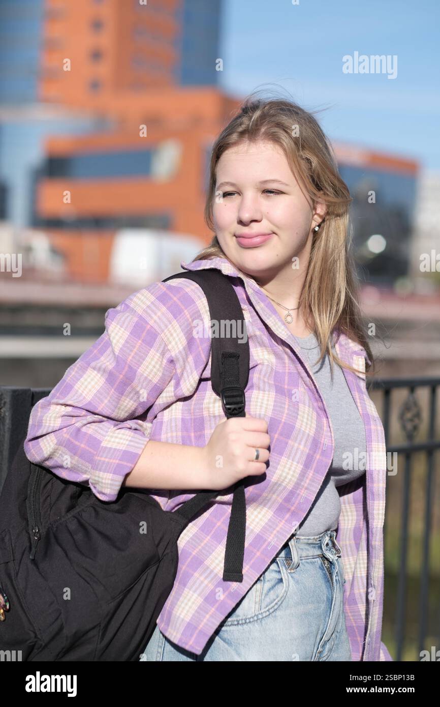 blonde girl, dressed casually, looks content as she stands outdoors ...