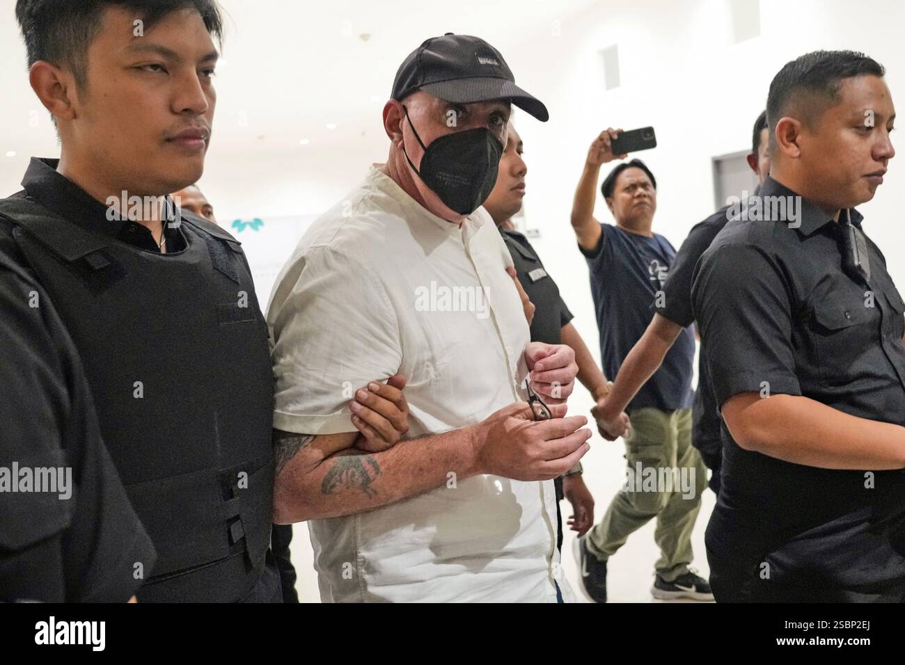 Security officers escort Serge Atlaoui, center, an ailing French ...