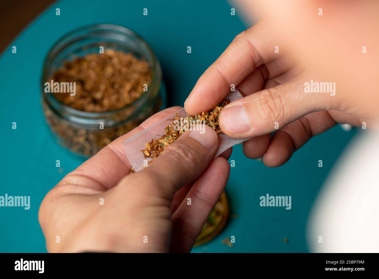 closeup of a man making a spliff, a joint made with some shredded ...