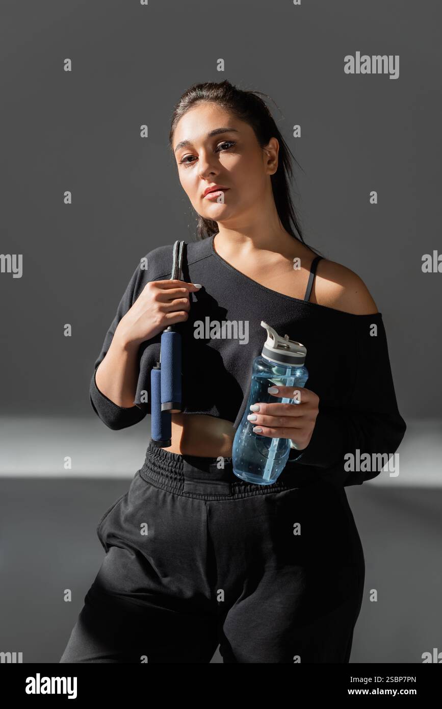 Confident woman poses with fitness gear, demonstrating strength and ...