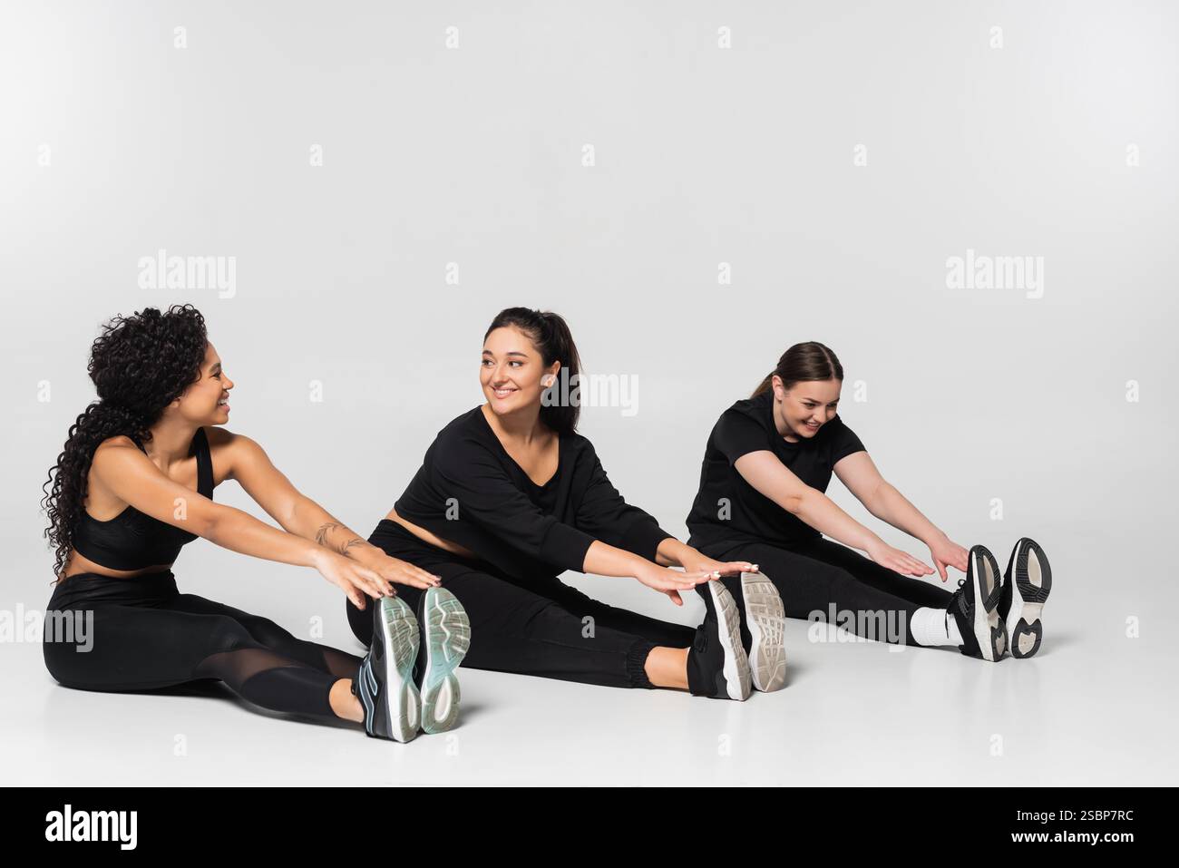 Three strong women stretch on a clean white background, showcasing ...