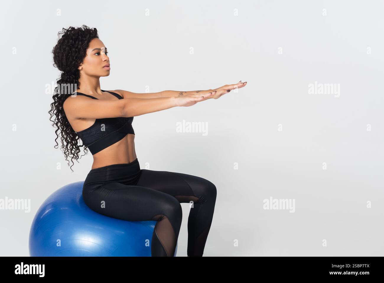 A fit woman in sportswear balances perfectly on a ball during her ...