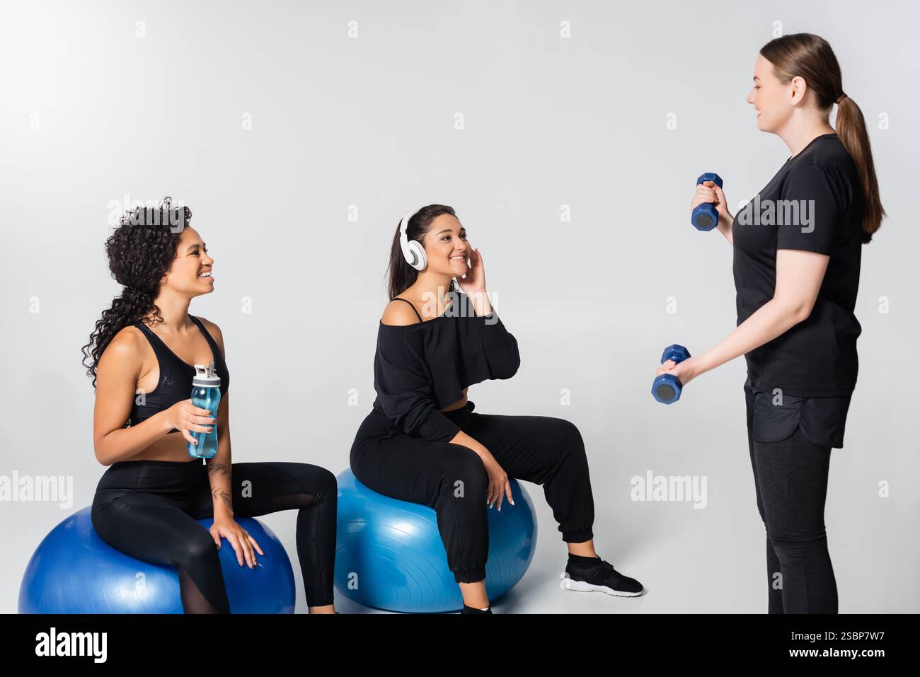 Three strong women enjoy an interactive fitness session, lifting ...