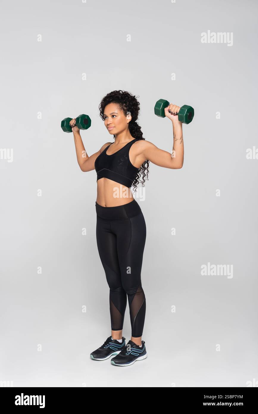 Strong woman engages in a dynamic workout, lifting weights with ...