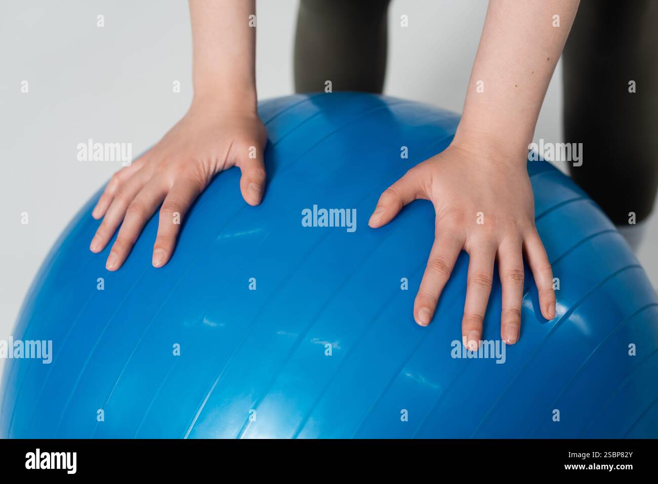 Female athlete balances on a blue exercise ball in a well lit fitness ...