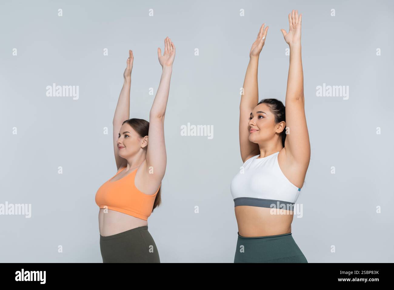 Two fit women express joy and strength while stretching upwards in ...