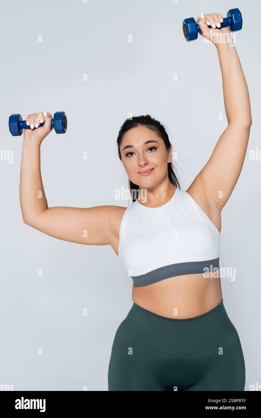 A strong woman engages in a dynamic workout, lifting weights with ...