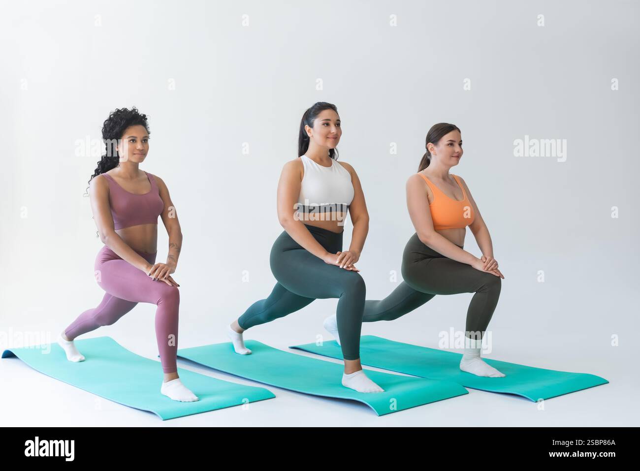 Three strong women perform lunges in colorful sportswear, showcasing ...