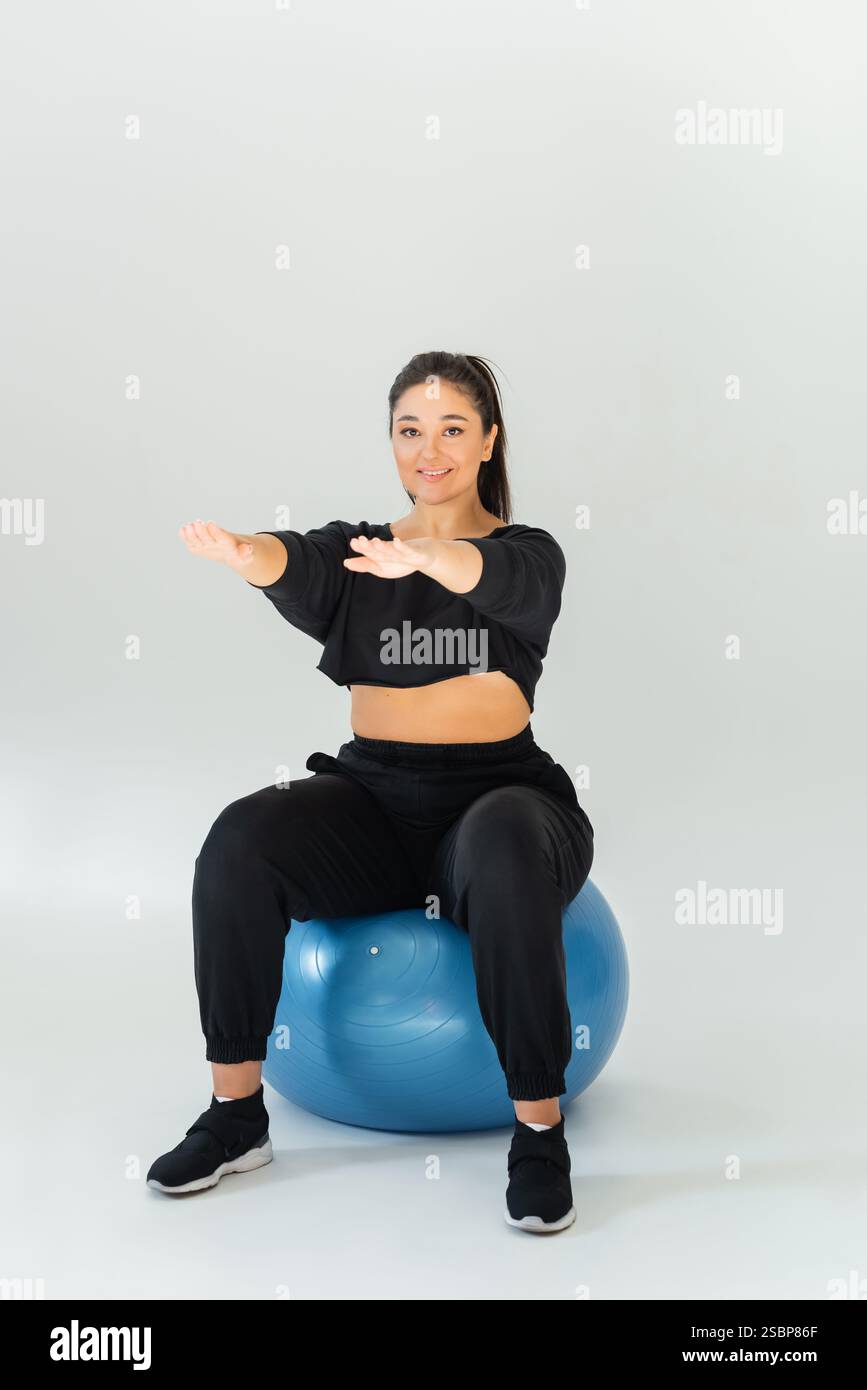 A fit woman engages in a dynamic workout session using a stability ball ...